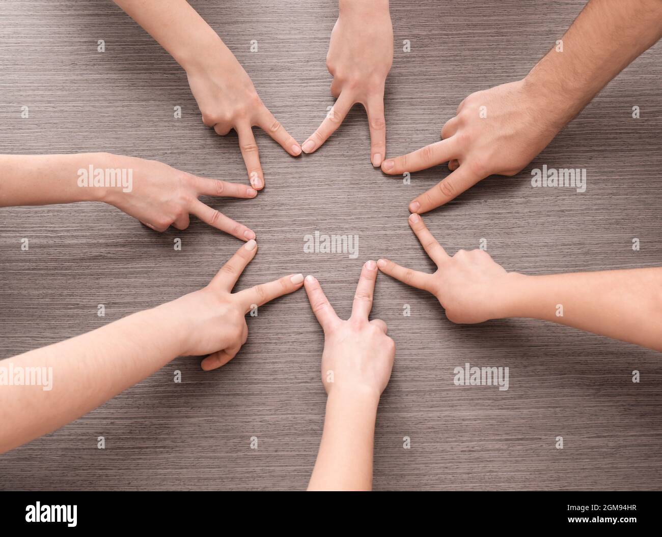 Group of people putting their hands together in circle on wooden ...