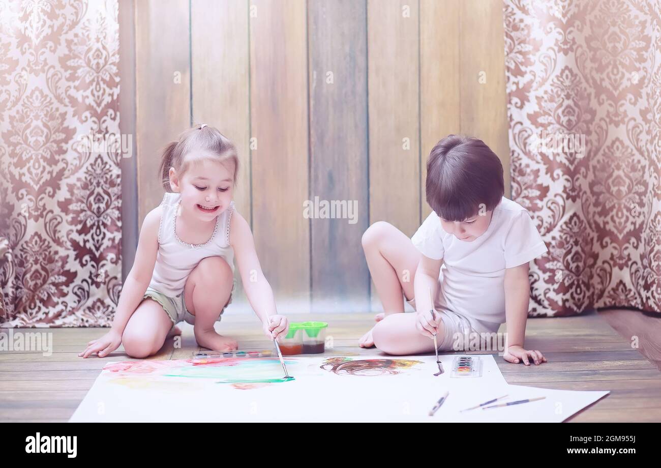 Little children paint on a large sheet of paper on the floor Stock ...