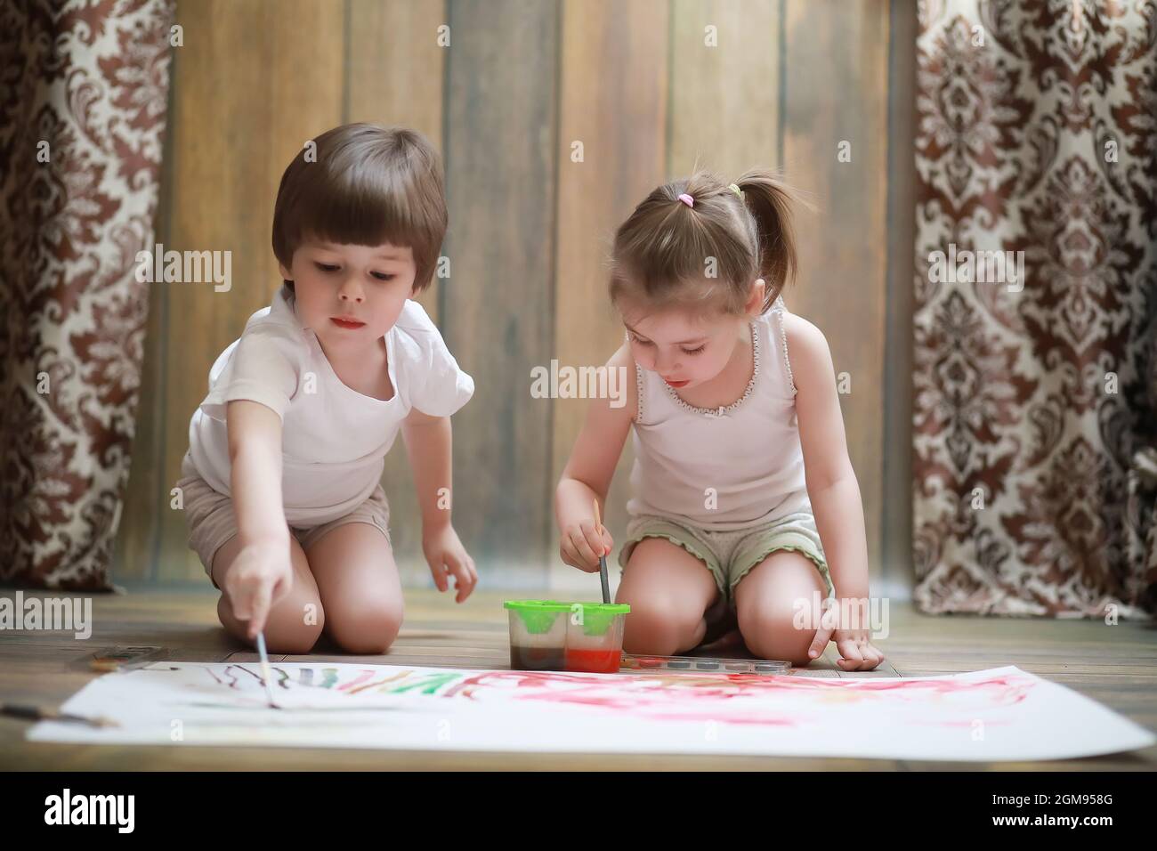 Little children paint on a large sheet of paper on the floor Stock ...