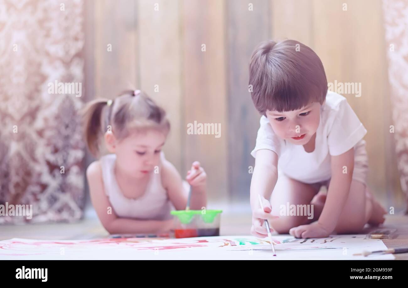 Little children paint on a large sheet of paper on the floor Stock ...