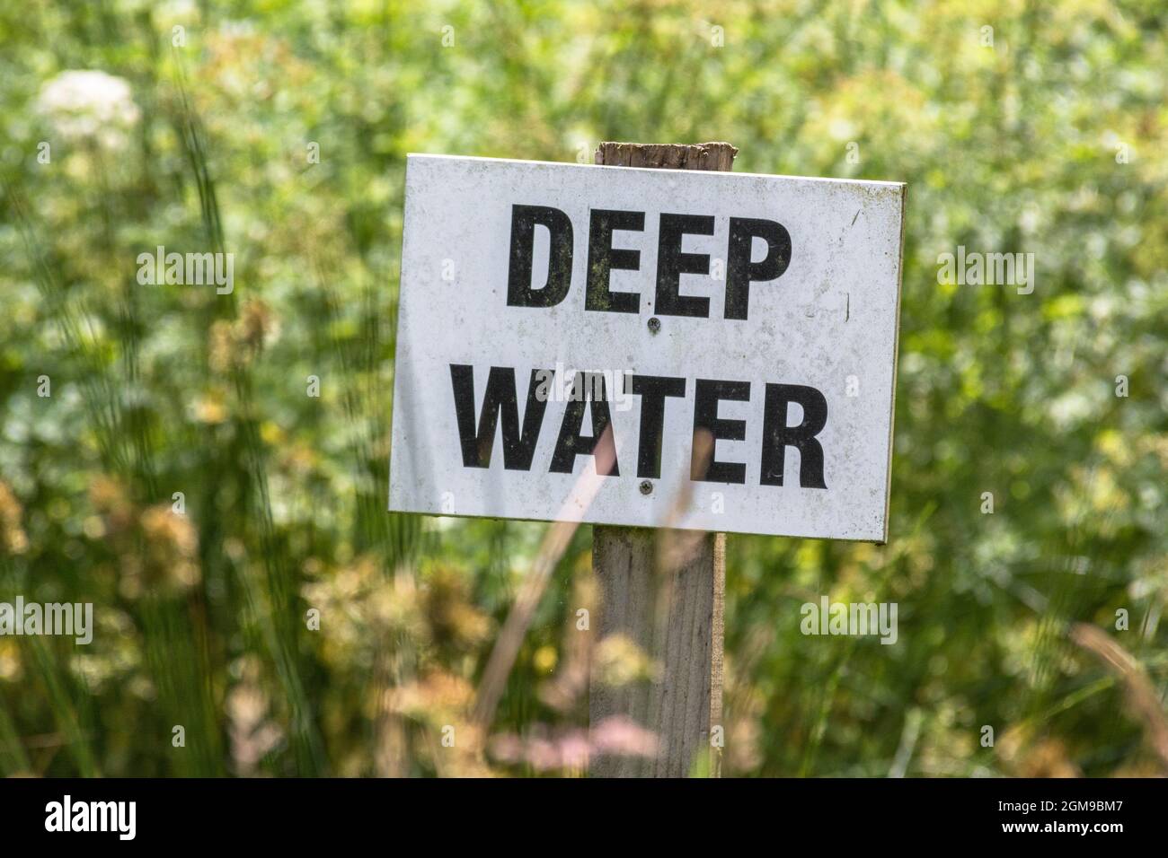 Deep Water warning sign at the side of a pond. Metaphor safety ...