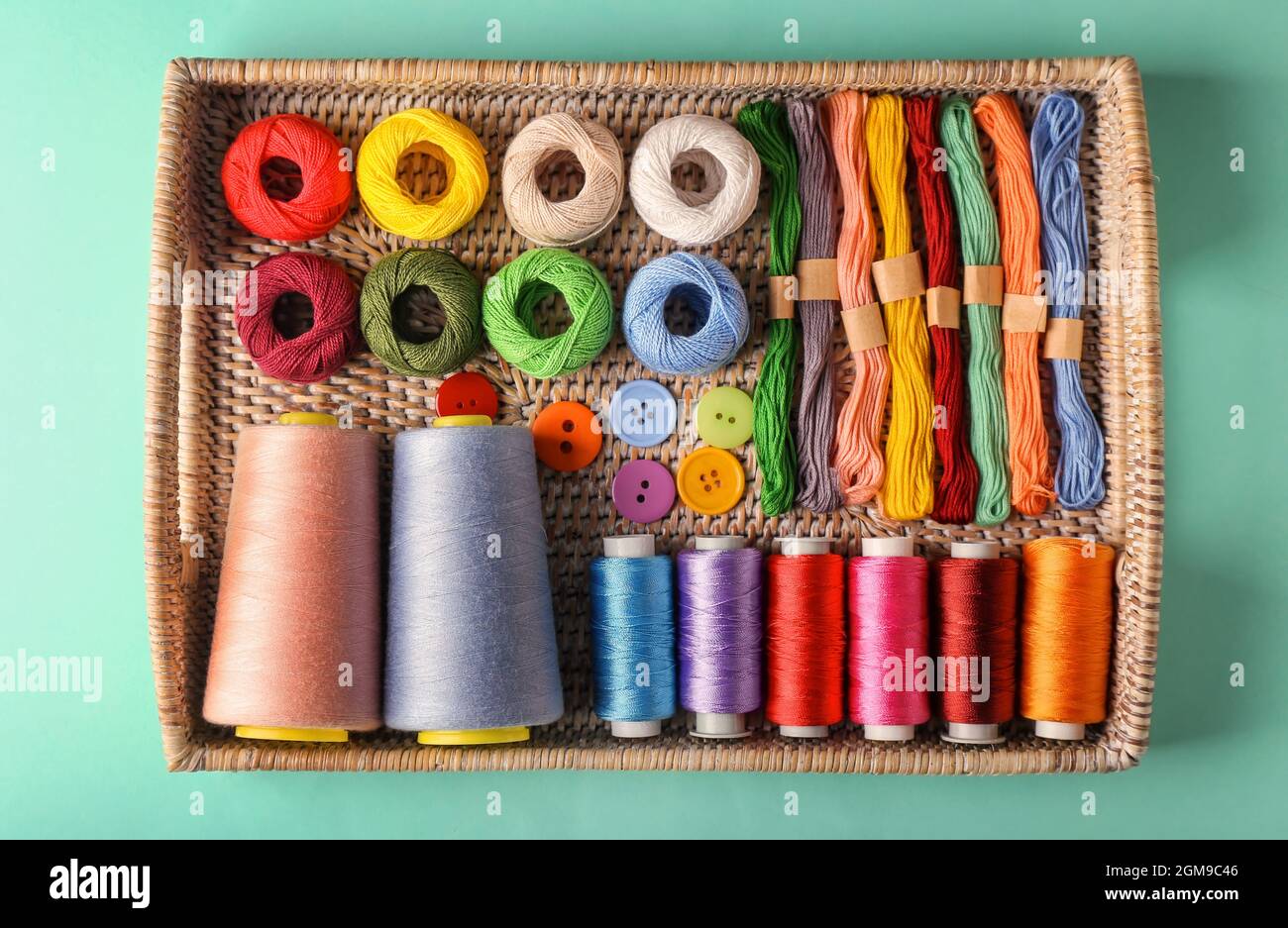 Wicker tray with different types of threads on color background Stock ...