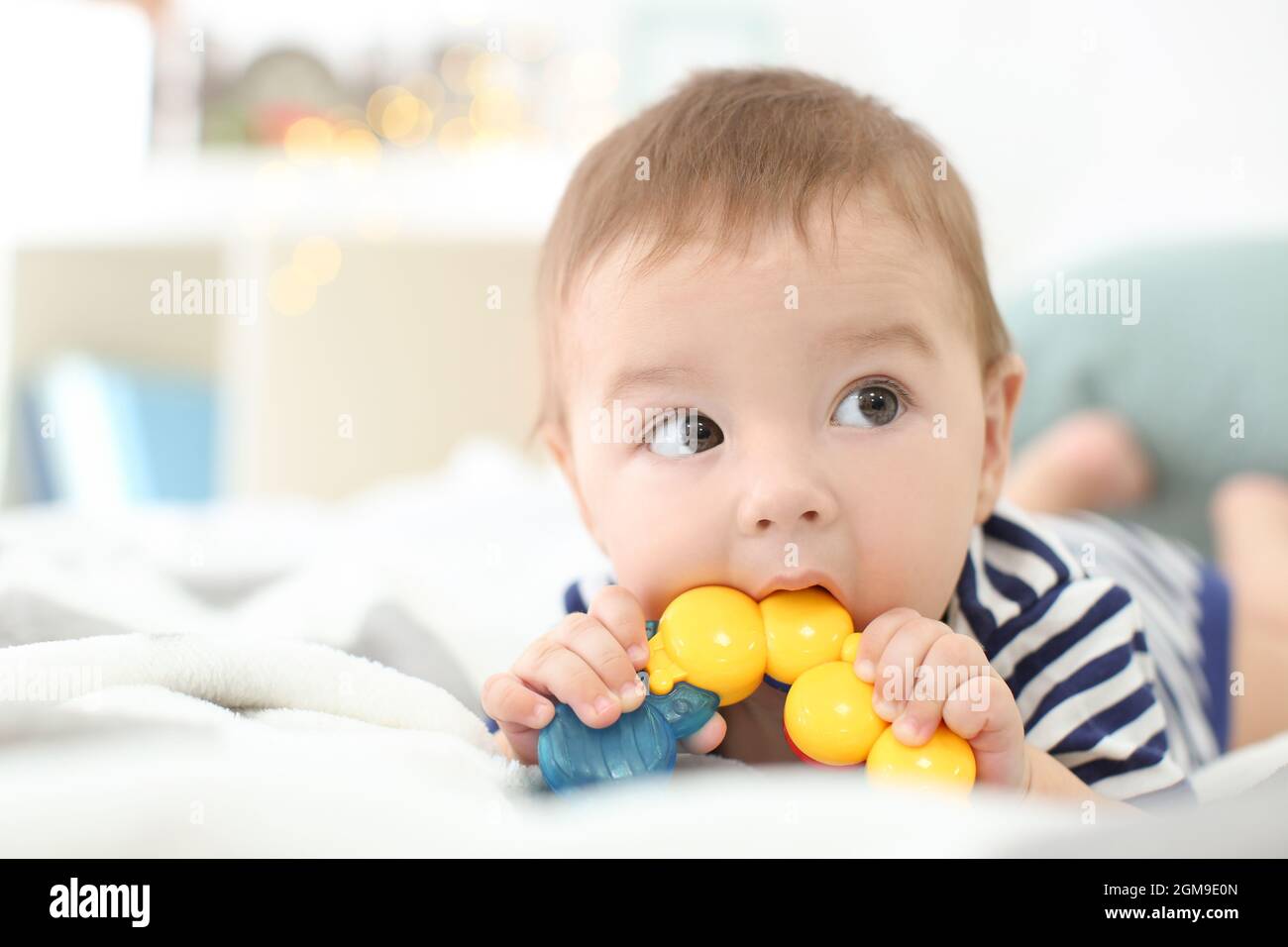 Cute baby with rattle lying on bed at home Stock Photo - Alamy