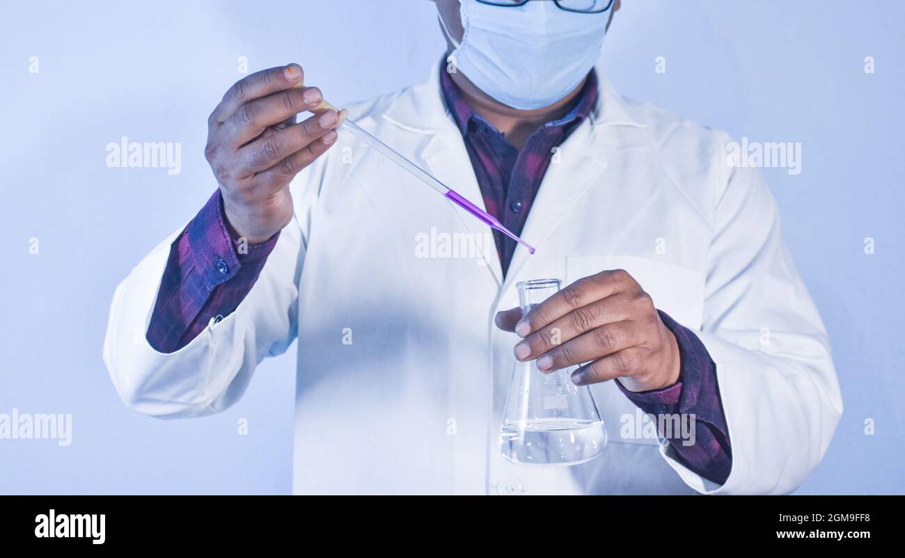 Scientist pouring color liquid into a conical flask with a dropper ...