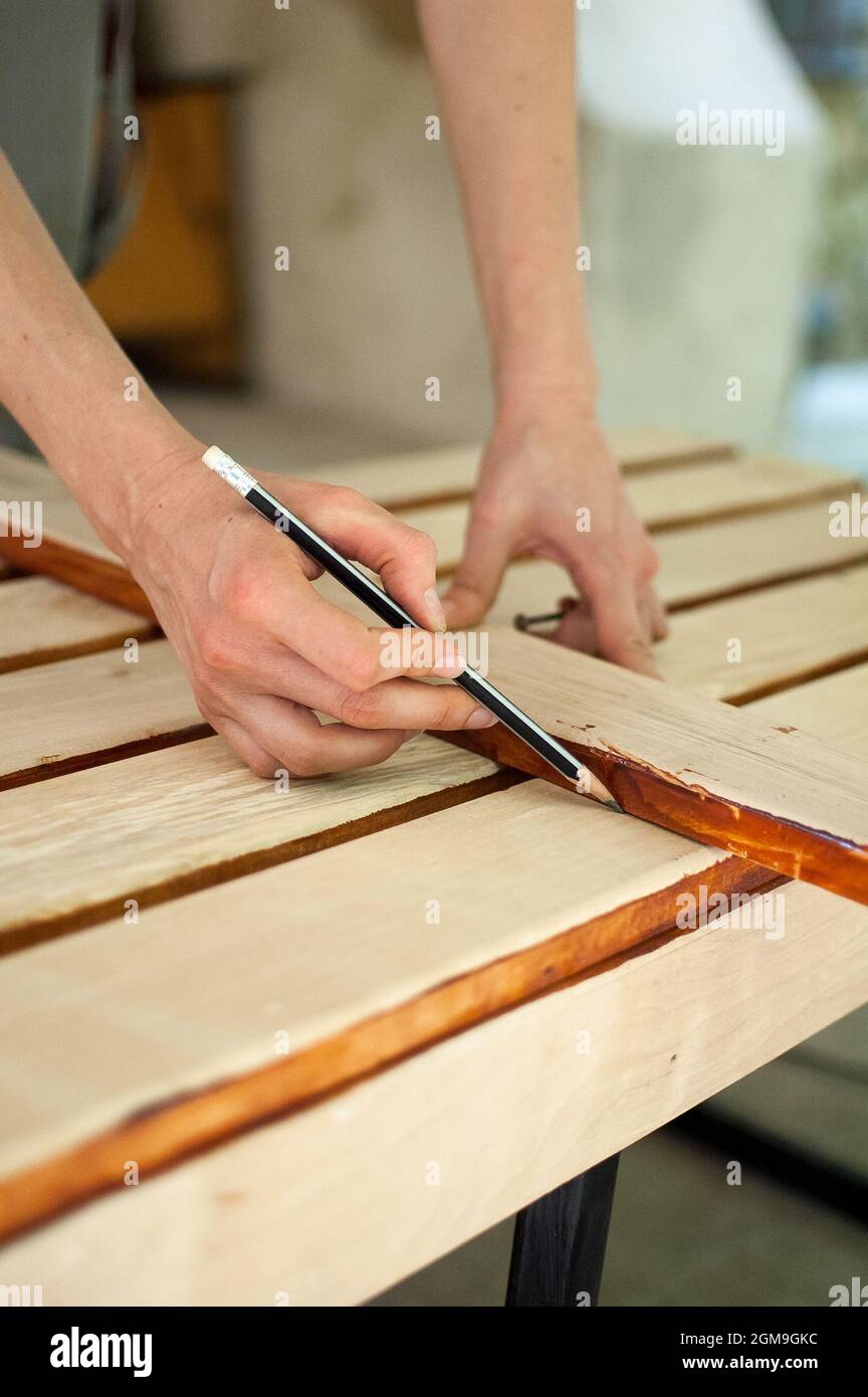 Female hands are making some marks on wooden plank for future holes ...