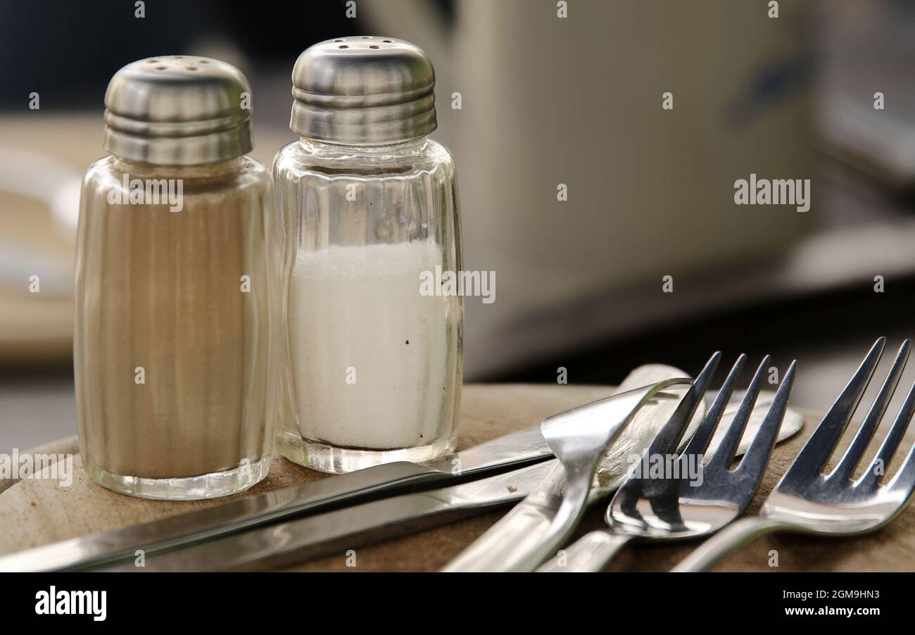 Closeup shot of salt and pepper shakers with forks on the table Stock ...