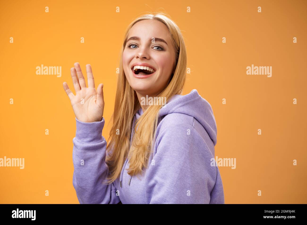 Waist-up friendly lucky cute blond girl waving palm happily smiling ...
