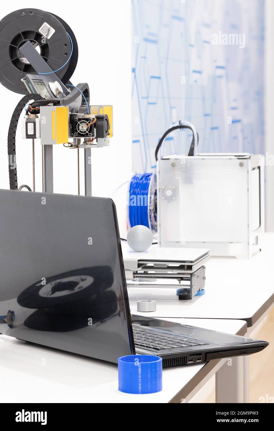 3D printers, rolls of 3D PLA filament, laptop and 3D printed plastic ...