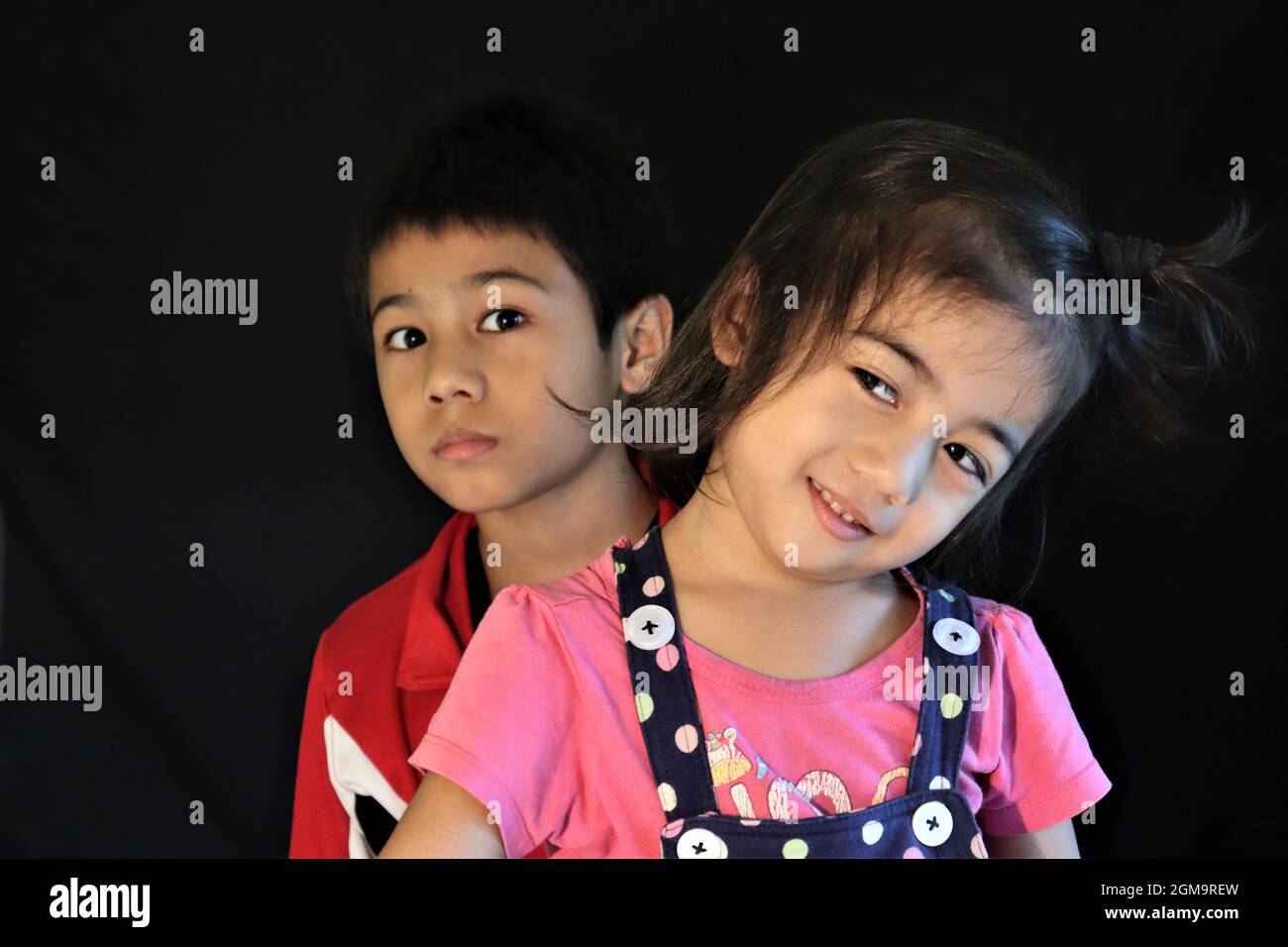 The brother standing behind his sister, they are making fun and ...