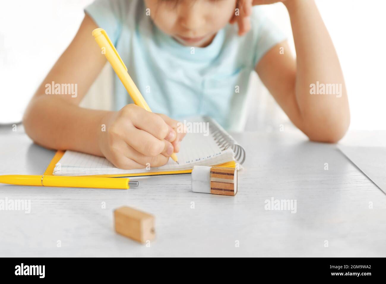 Little girl doing homework against white background Stock Photo - Alamy