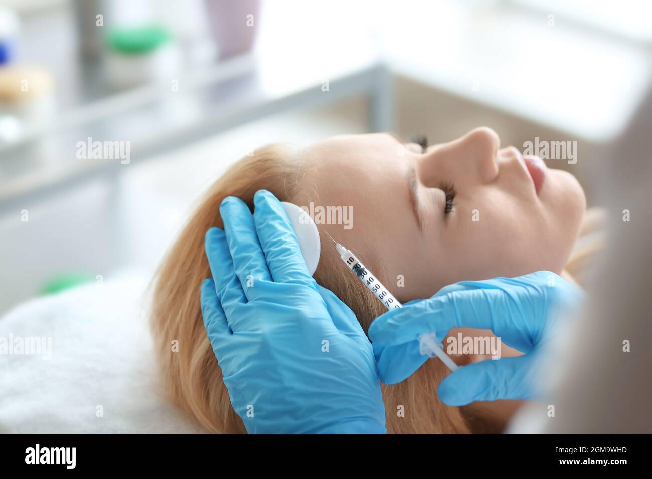 Young woman with hair problem receiving injection in clinic, closeup ...