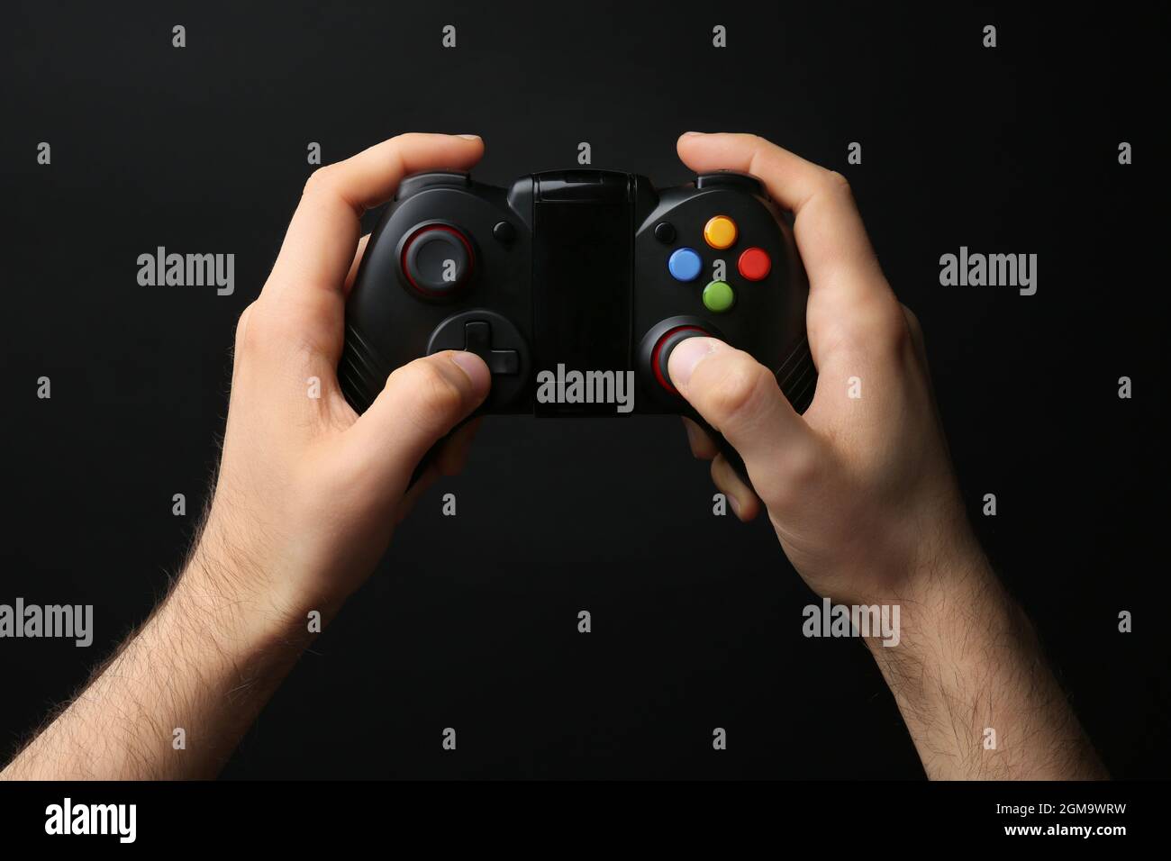 Man holding video game controller on black background Stock Photo - Alamy