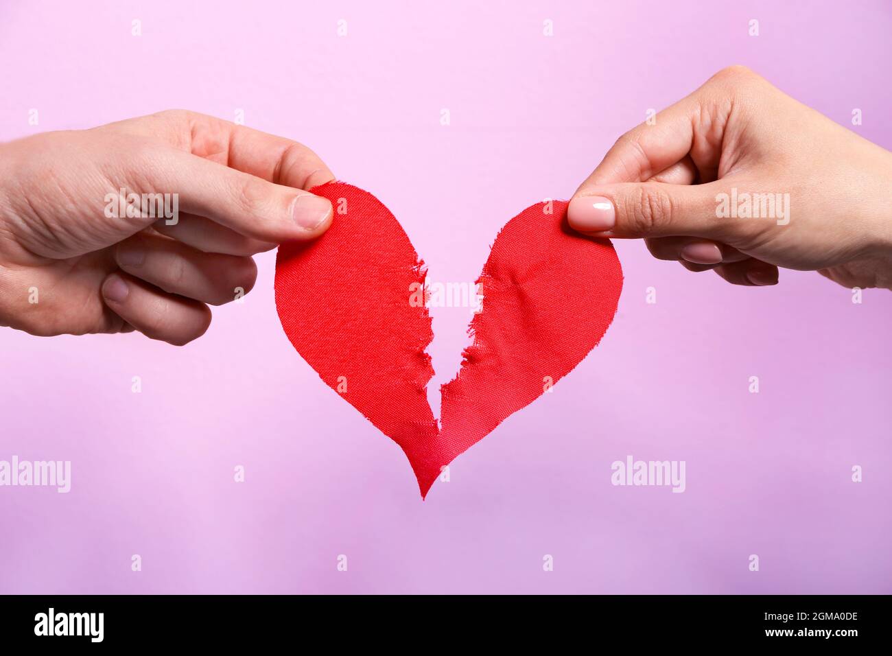 Couple tearing paper heart in half on color background, closeup ...