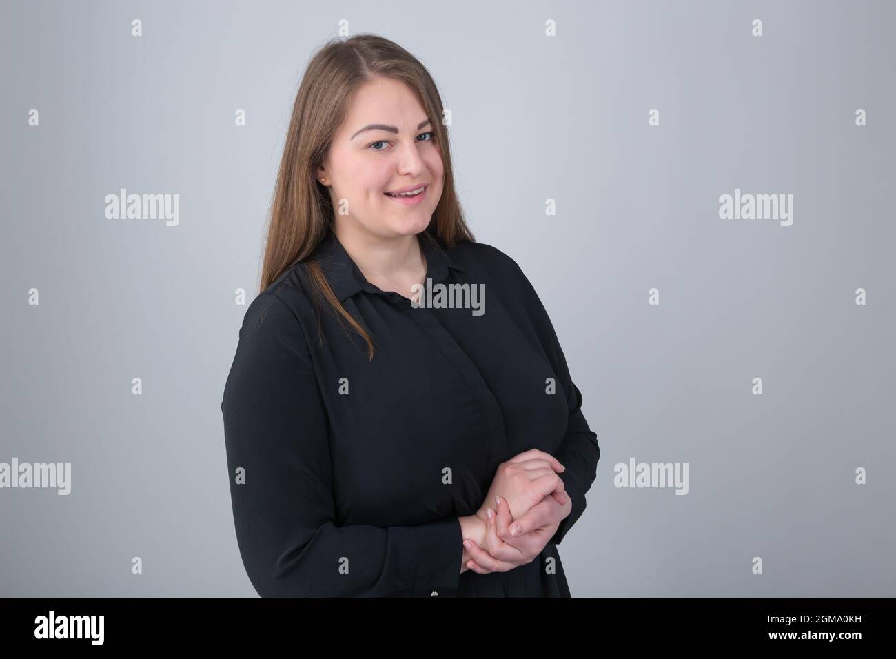 Smiling young overweight woman in black shirt posing in studio. Plus ...