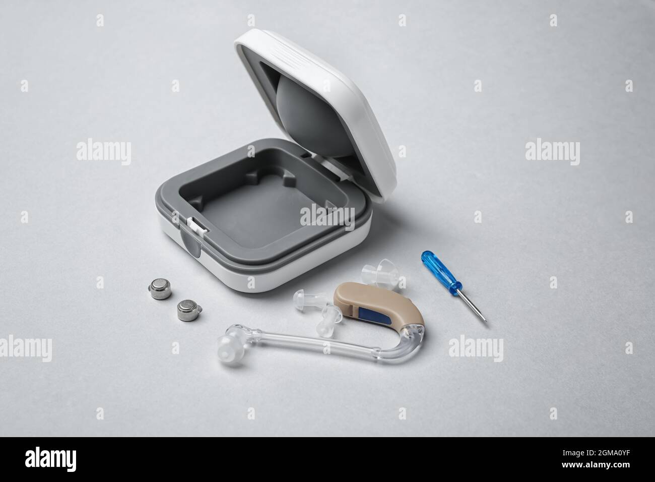 Hearing aid with accessories on light background Stock Photo - Alamy