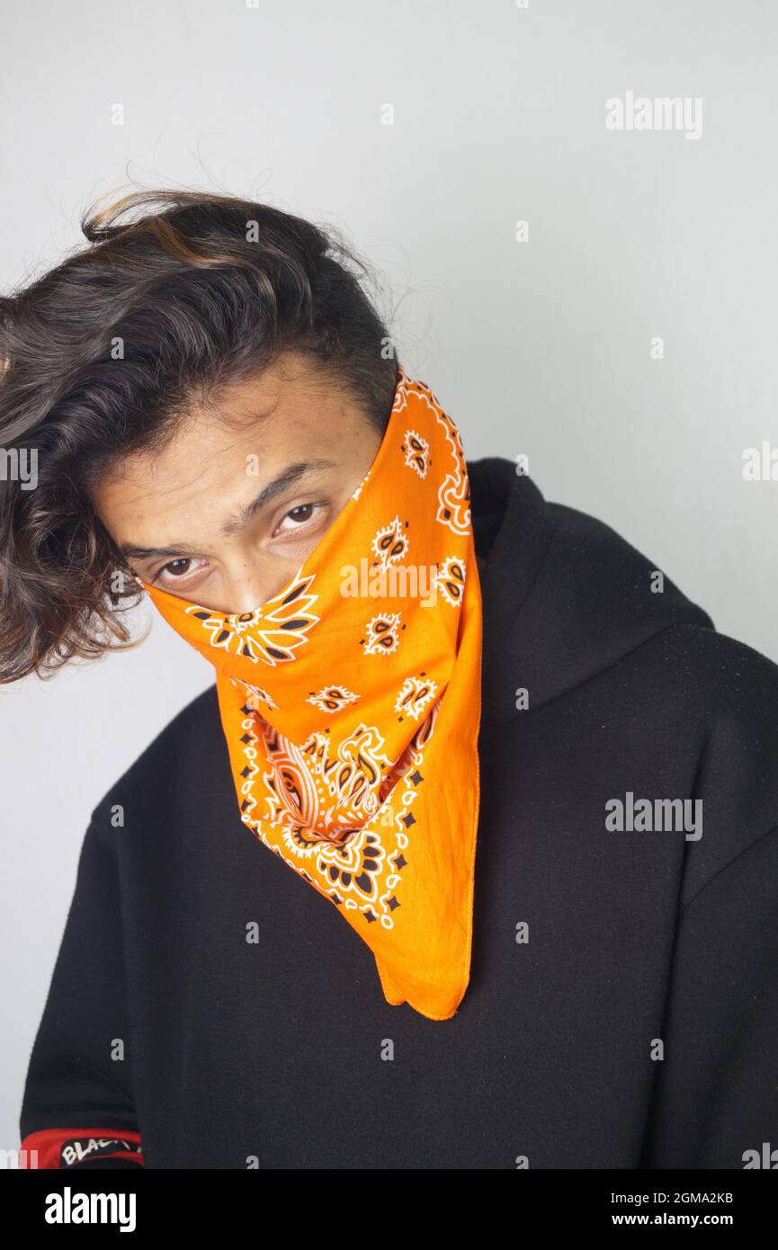 Stylish Indian male wearing an orange bandana posing against the white ...