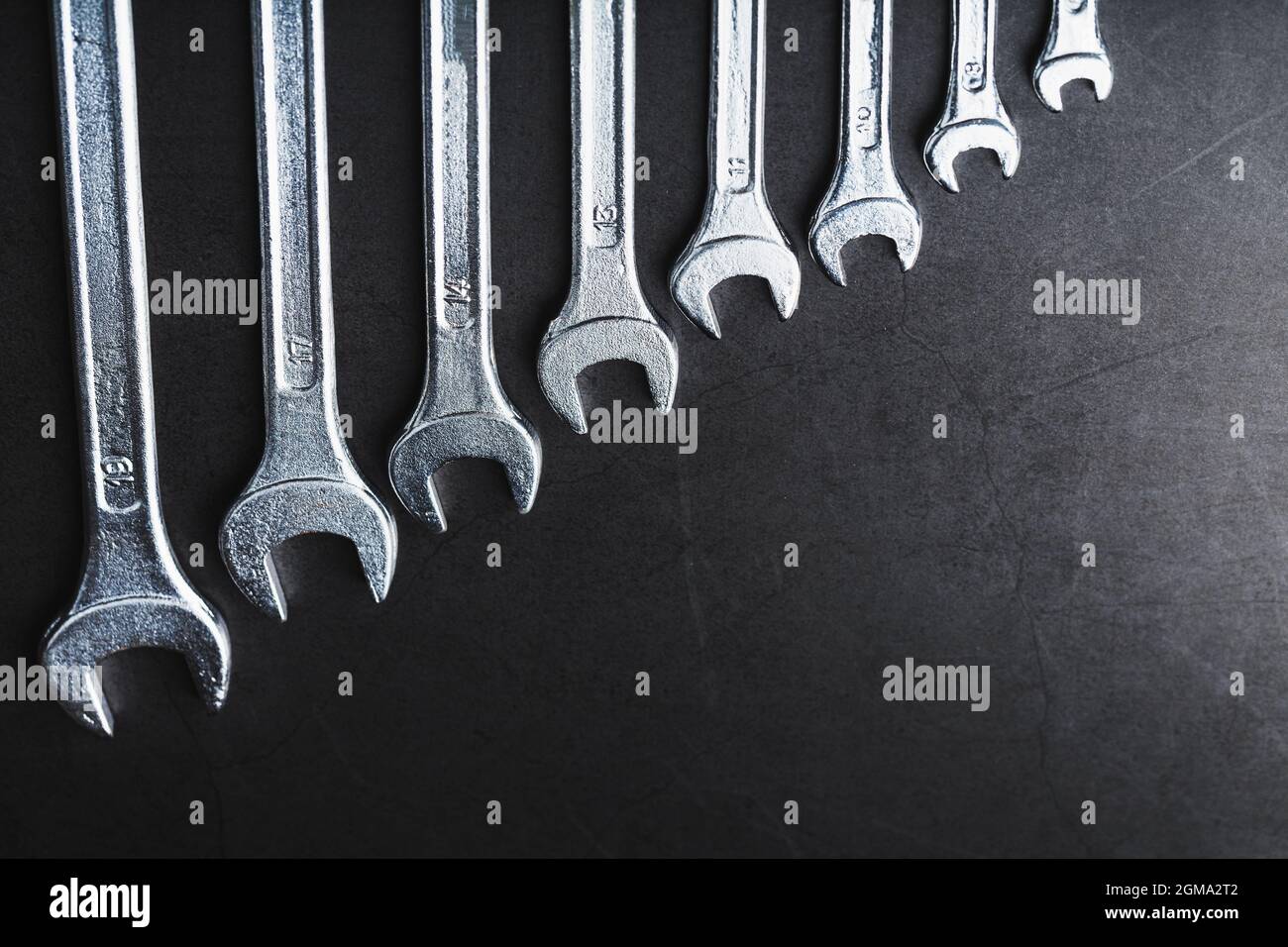 A set of wrenches on a textured black background in a row. Top view ...