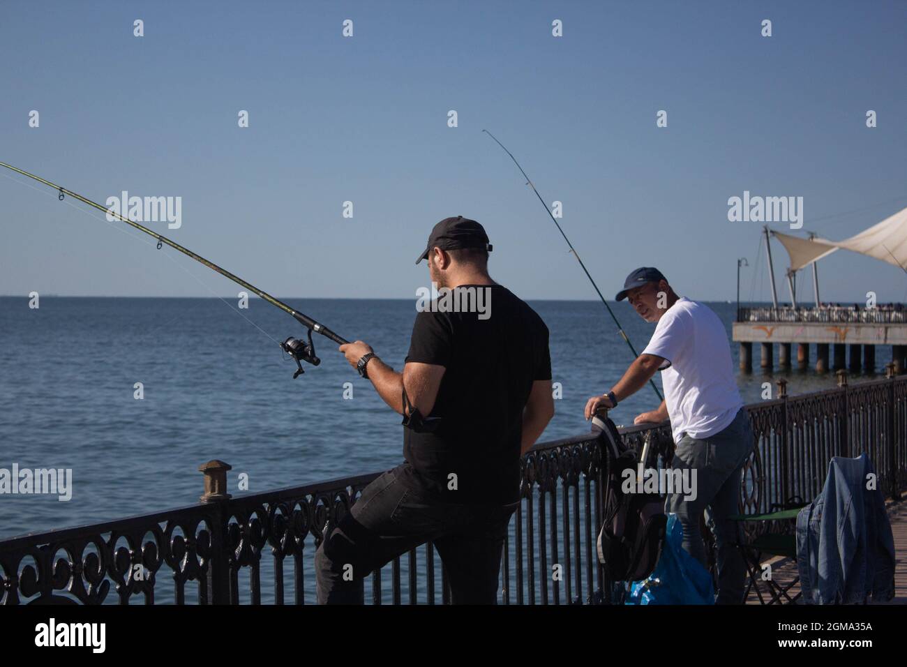 two man having a conversation while fishing on a pier. expressing ...