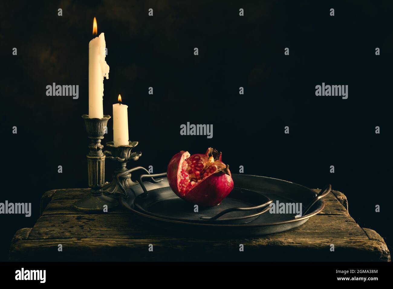 Still life on wooden table with antique plates and a pomegranate cut ...