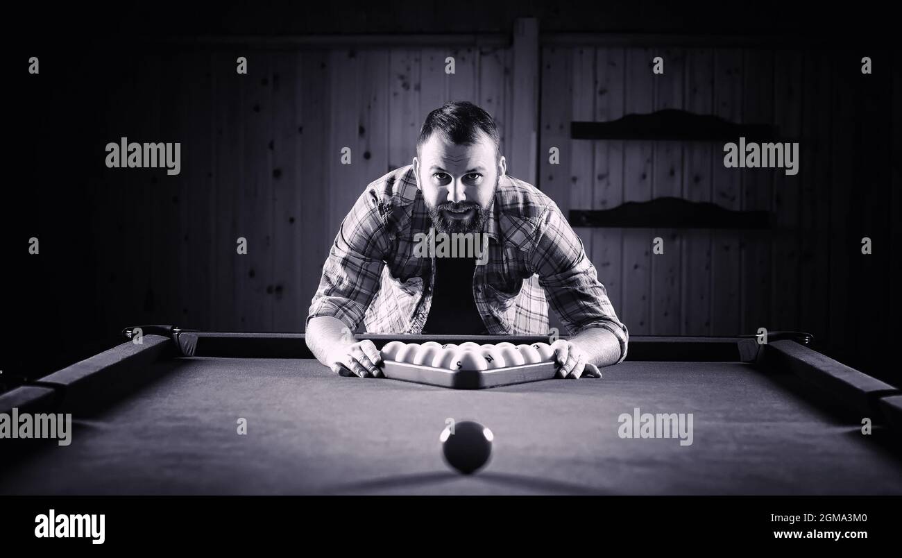 A man with a beard plays a big billiard. Party in 12-foot pool ...
