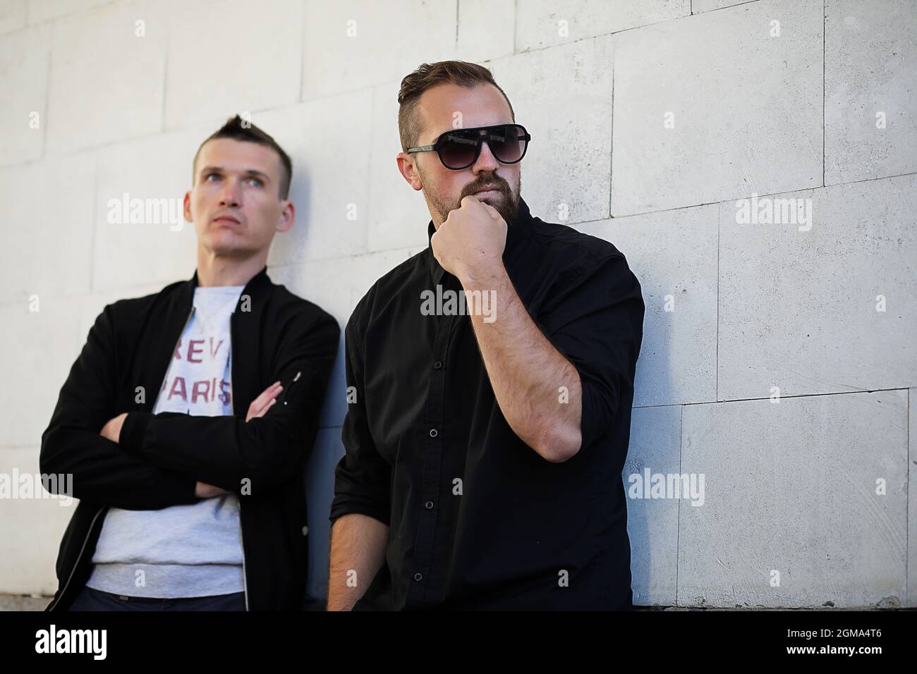 Two men in sunglasses against a brick wall background Stock Photo - Alamy