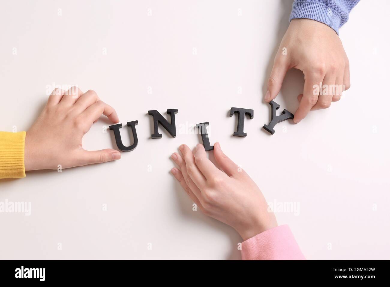 Group of people making word UNITY from letters on white background ...