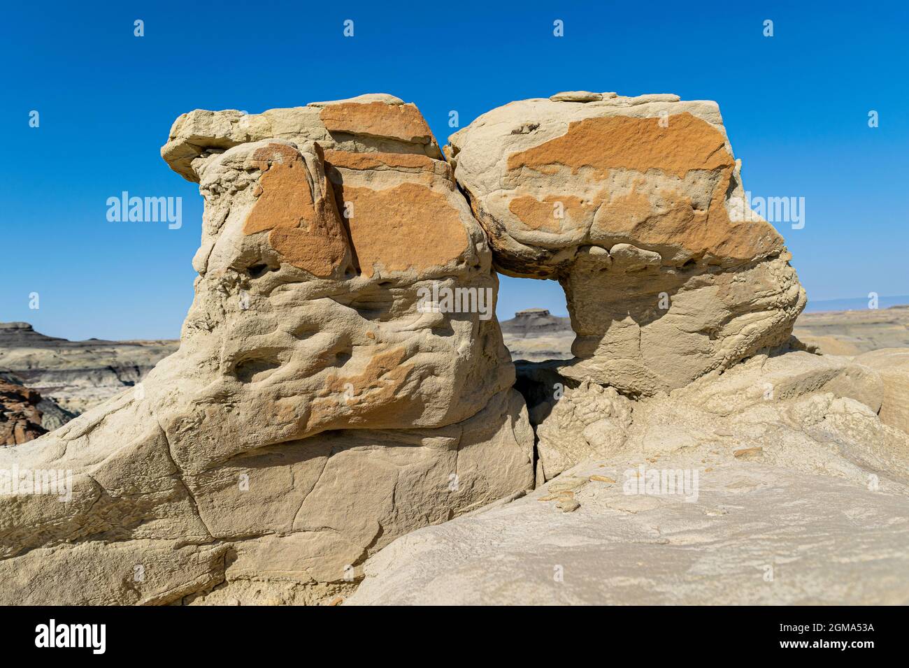 Two kissing rocks form a window looking out at the distant Bisti ...