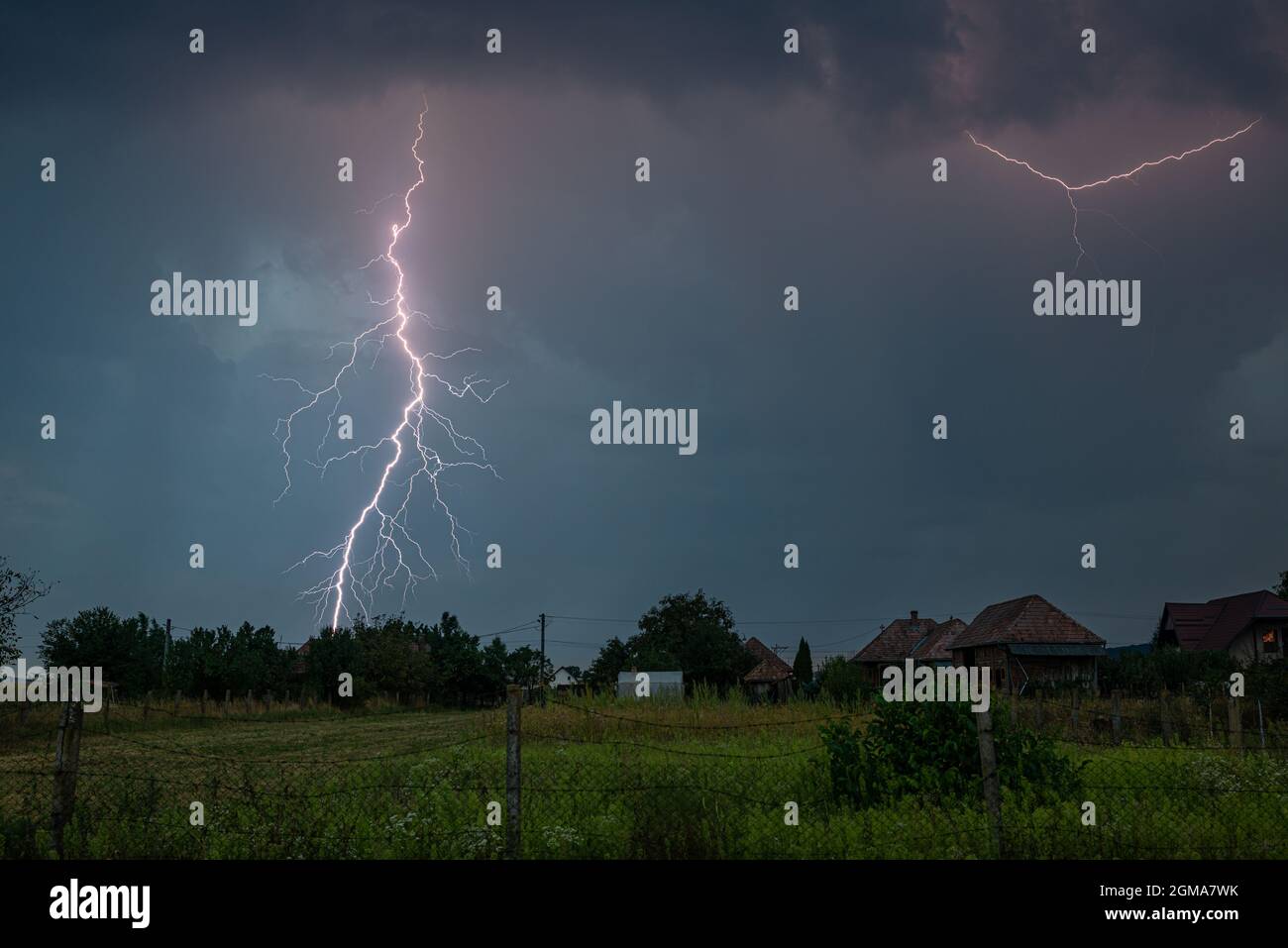 A powerful bolt of lightning strikes near a village in Romania Stock ...