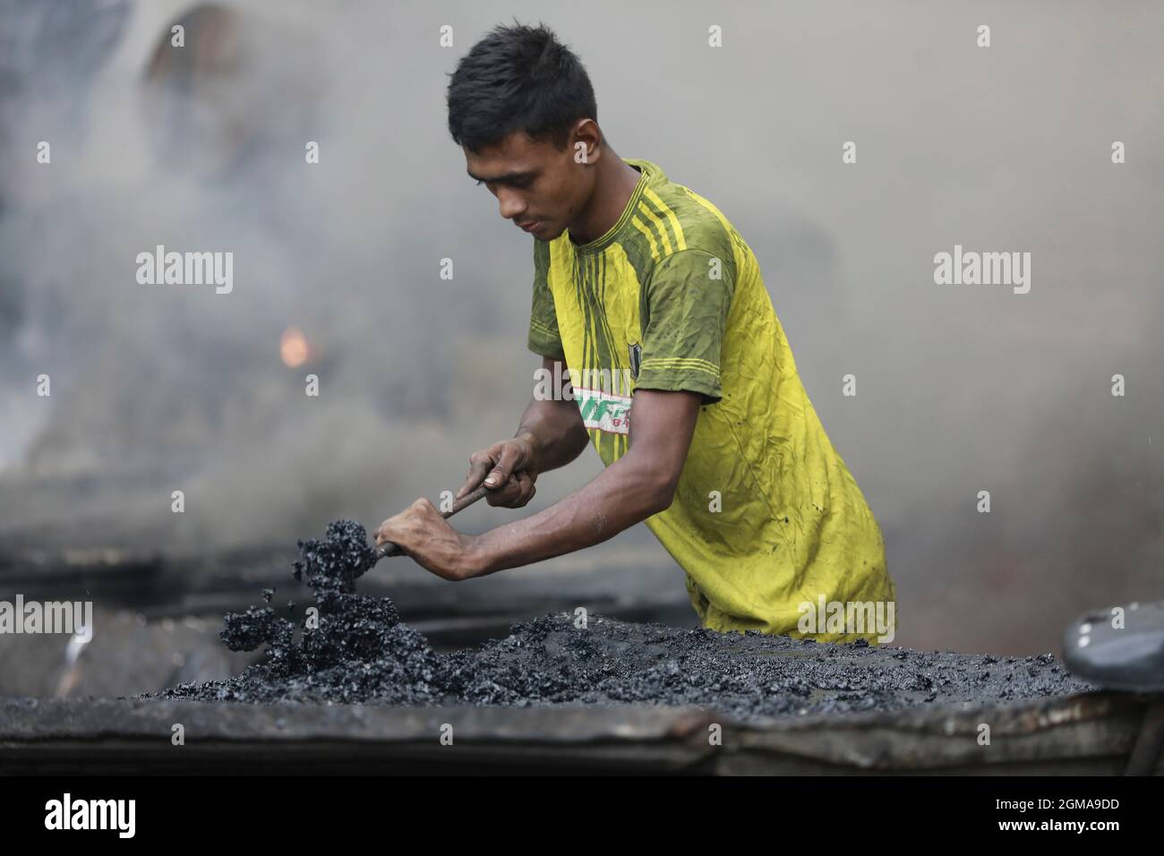 A Bangladeshi worker works at a road construction site in Dhaka ...