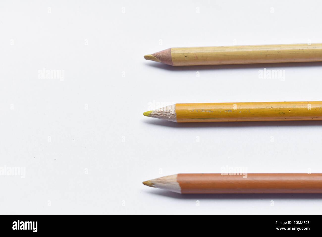 Parallel yellow and orange painting pencils isolated on a white ...