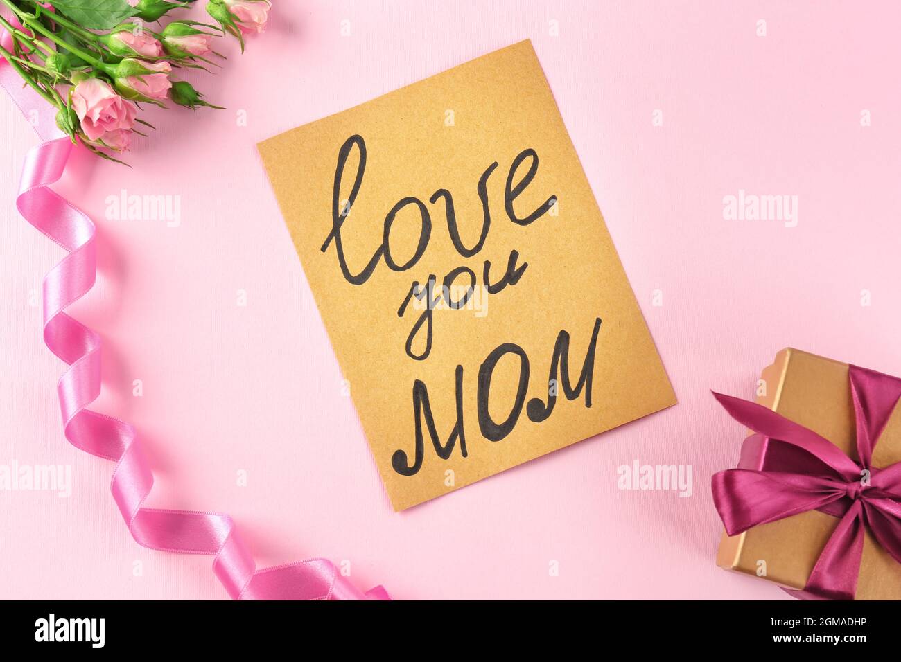 Card with text "LOVE YOU MOM", flowers and gift box on color background ...