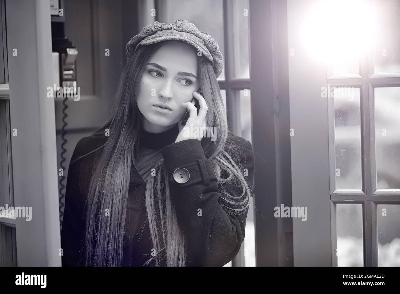 Beautiful young girl in a phone booth. The girl is talking on the phone ...