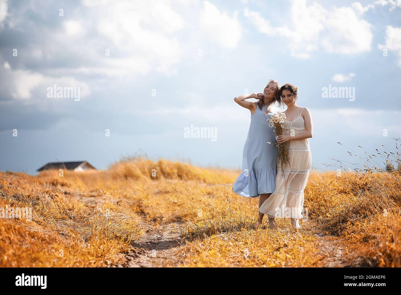 Two beautiful girls in dresses in autumn field have fun Stock Photo - Alamy