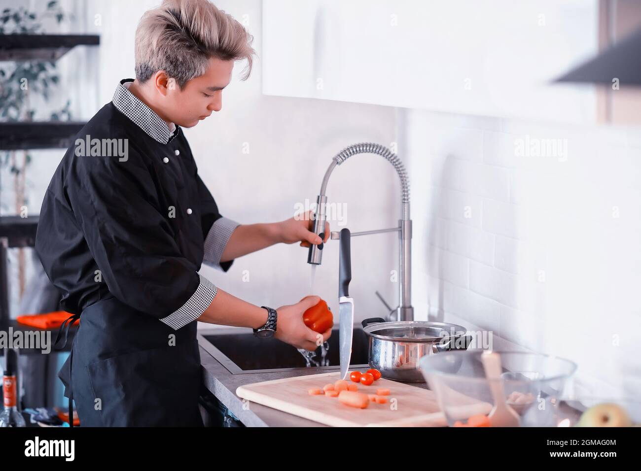 A young Asian cook in the kitchen prepares food in a cook suit Stock ...