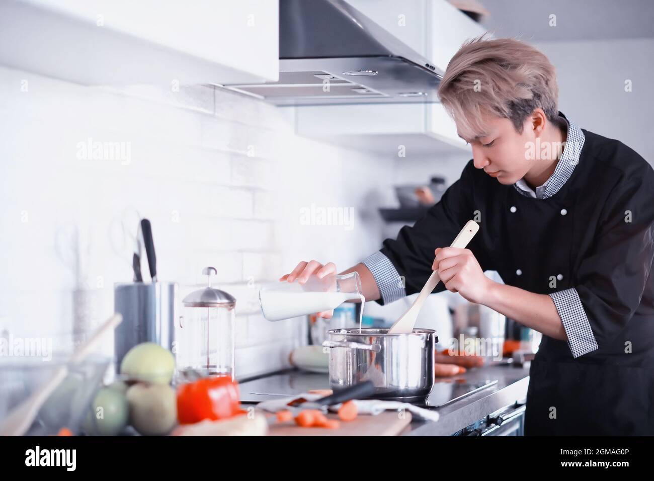 A young Asian cook in the kitchen prepares food in a cook suit Stock ...