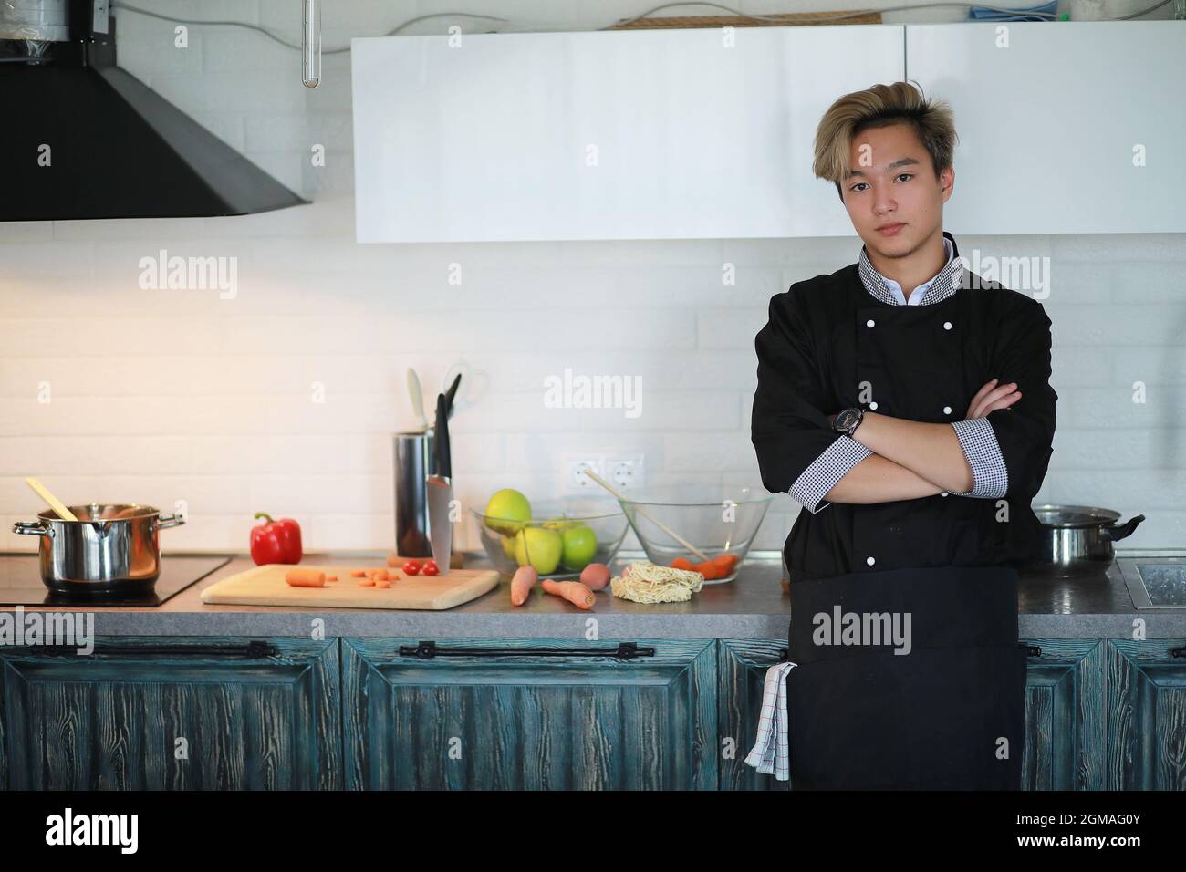 A young Asian cook in the kitchen prepares food in a cook suit Stock ...