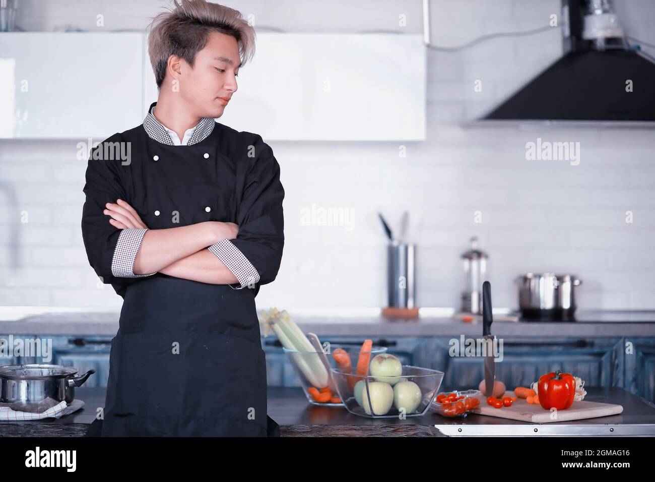 A young Asian cook in the kitchen prepares food in a cook suit Stock ...