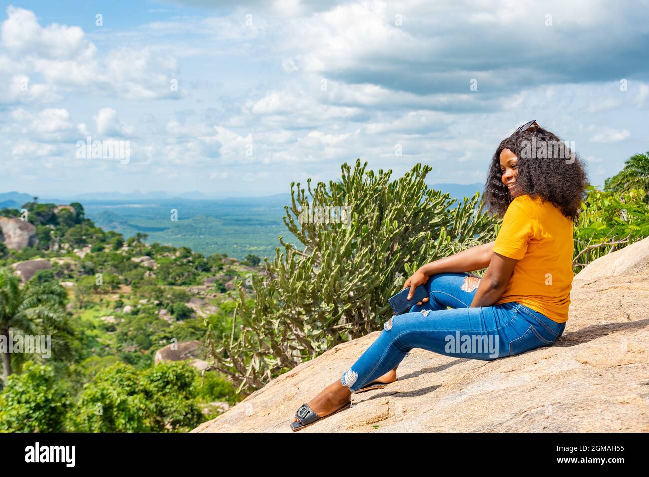 young african woman sitting on a rock Stock Photo - Alamy