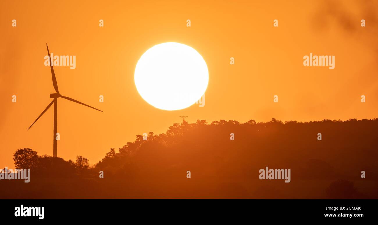 Sunrise with a large sun rising from behind a mountain next to a ...