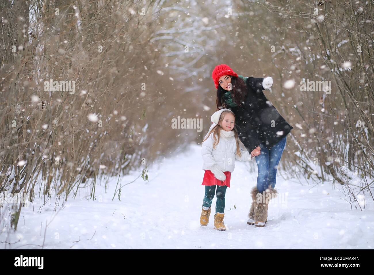Winter fairy tale, a young mother and her daughter ride a sled in the ...