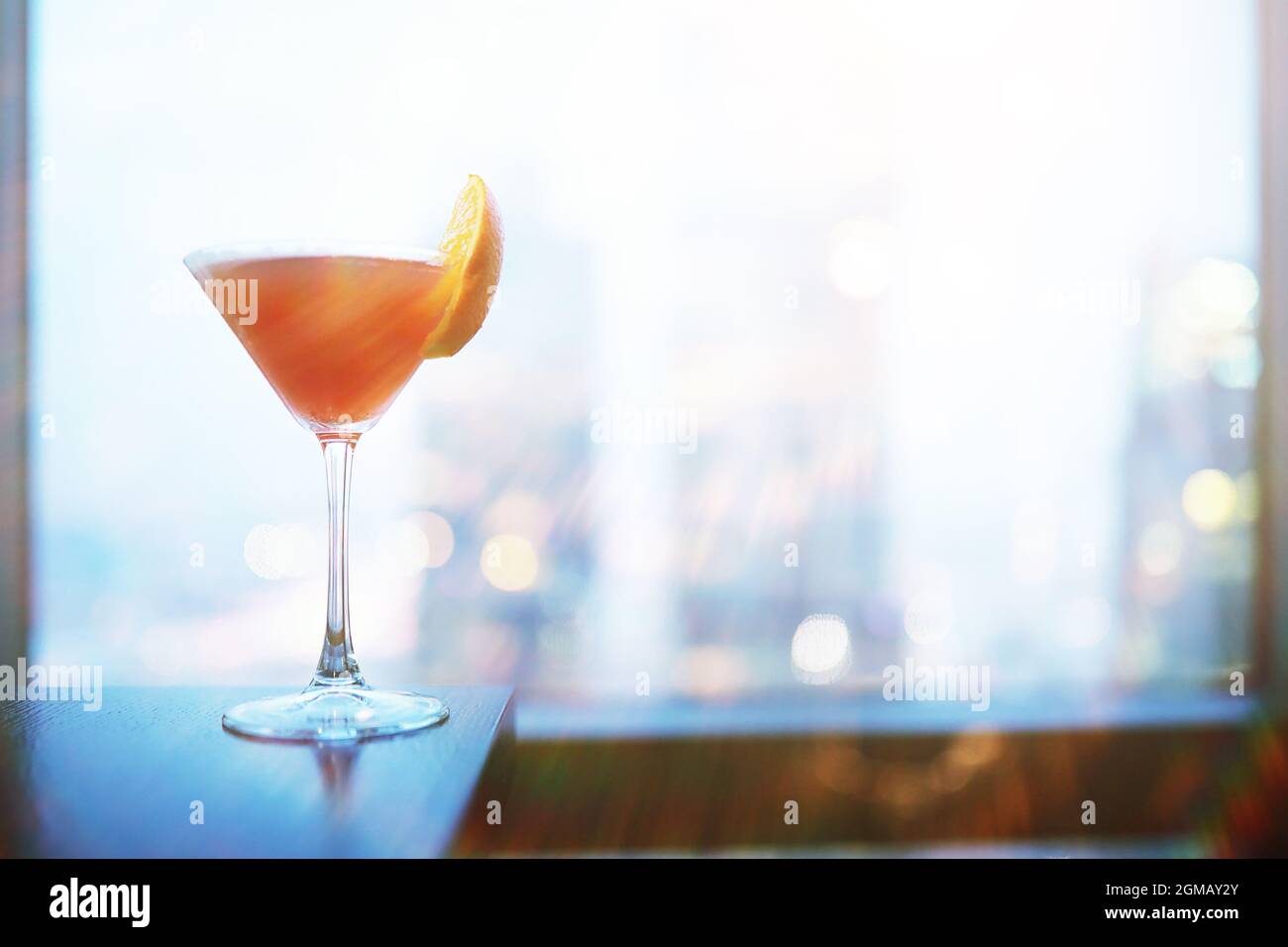 Cocktail glasses on the windowsill by the glass of a tall building ...