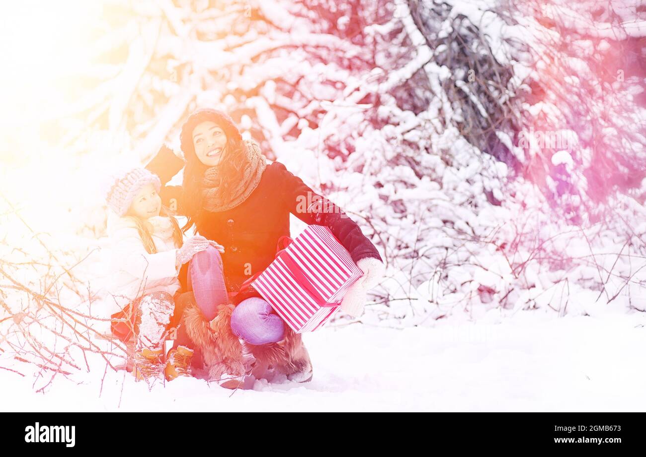 Winter fairy tale, a young mother and her daughter ride a sled in the ...
