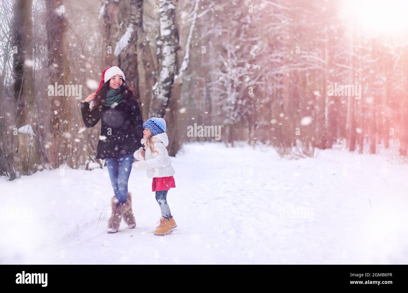 Winter fairy tale, a young mother and her daughter ride a sled in the ...