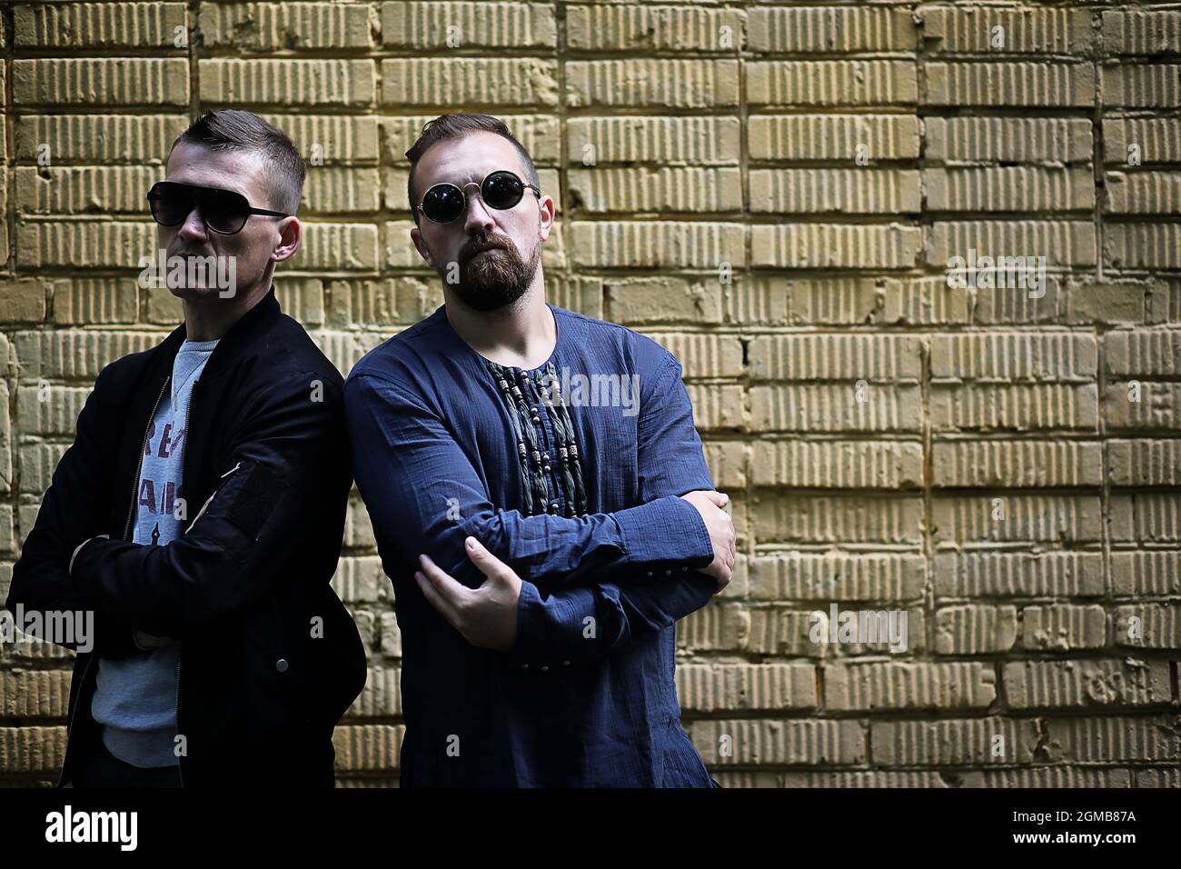 Two men in sunglasses against a brick wall background Stock Photo - Alamy