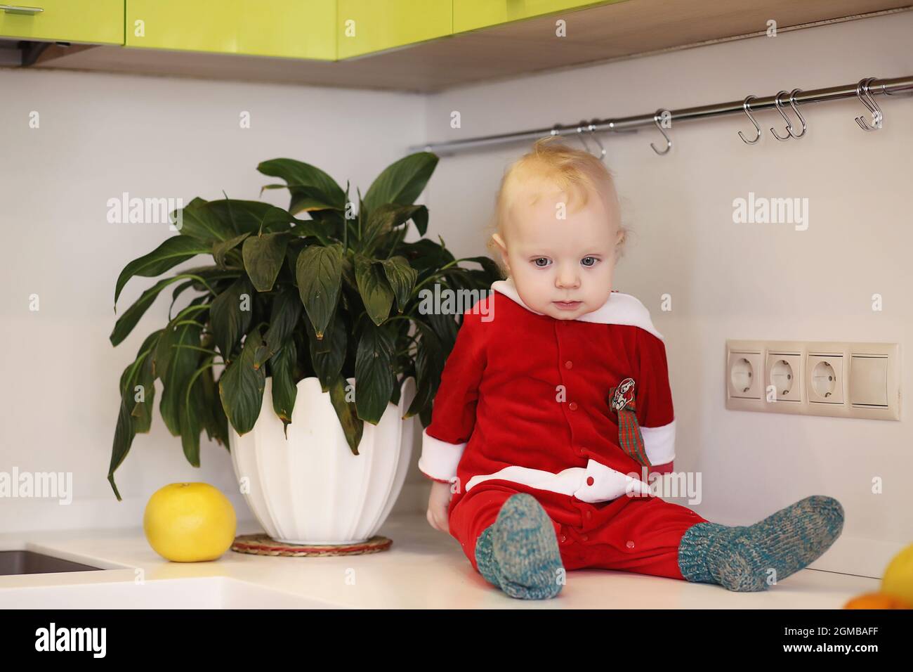 Little blond child in the kitchen sits on a table Stock Photo - Alamy