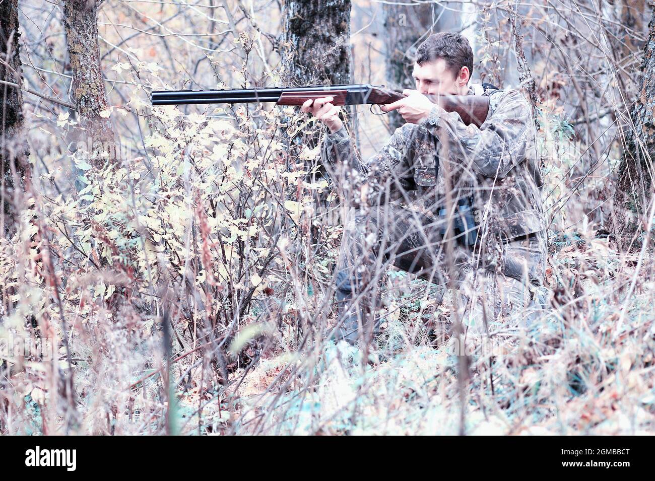 man in camouflage and with a hunting rifle in a forest on a spring hunt ...