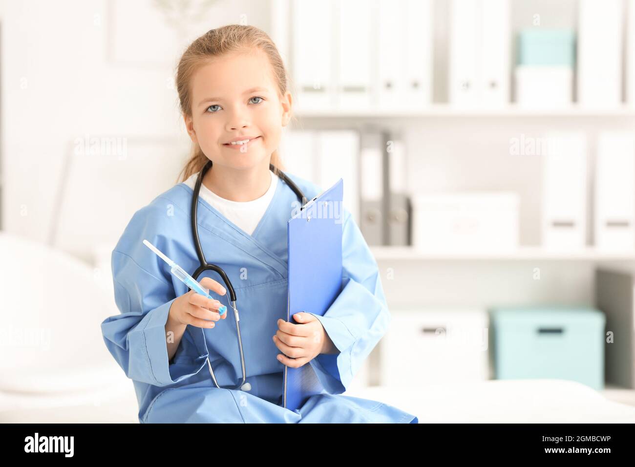 Cute little girl in doctor uniform with clipboard in hospital Stock ...