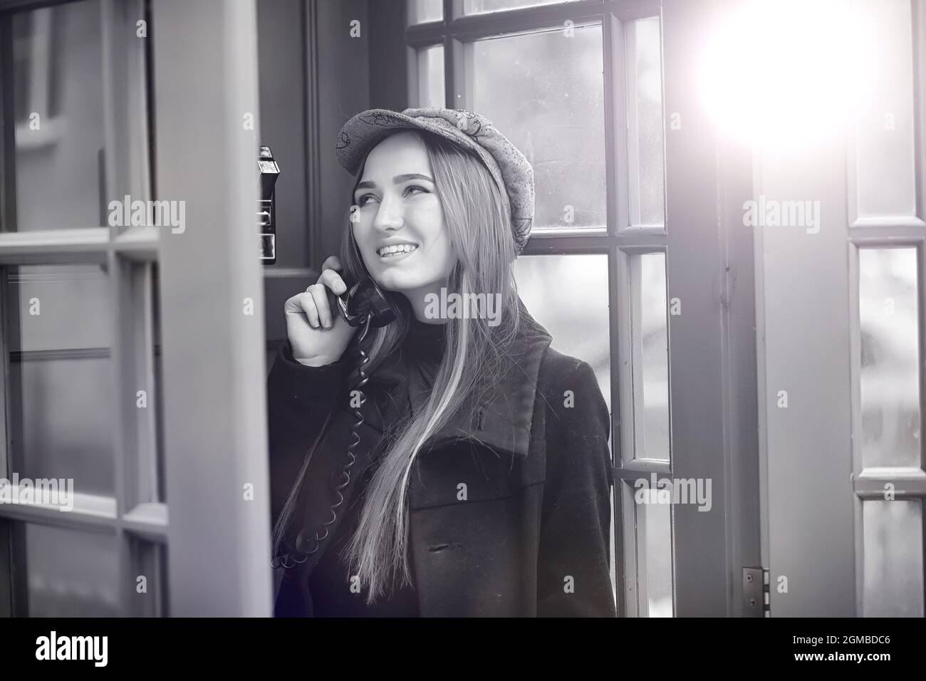 Beautiful young girl in a phone booth. The girl is talking on the phone ...