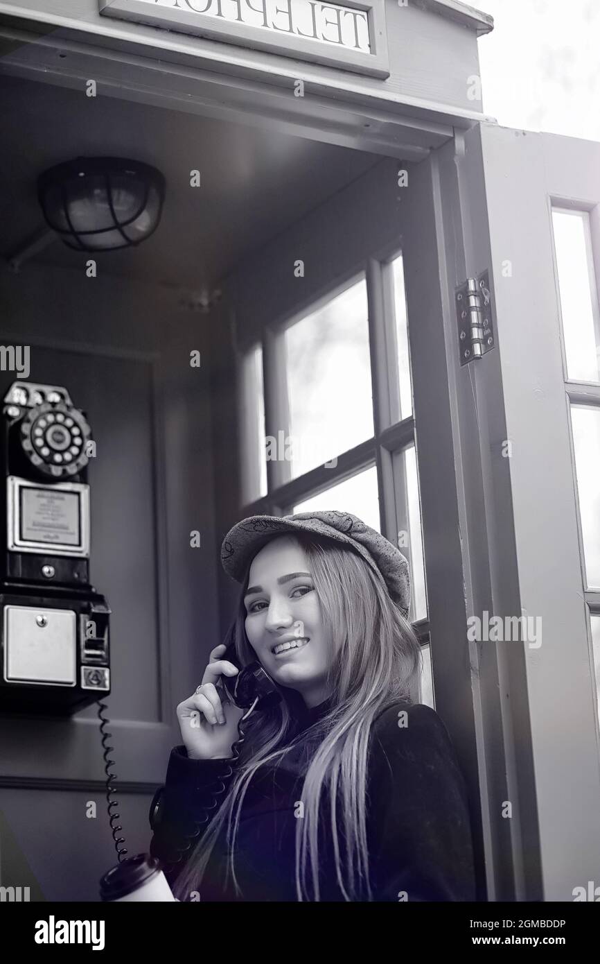 Beautiful young girl in a phone booth. The girl is talking on the phone ...