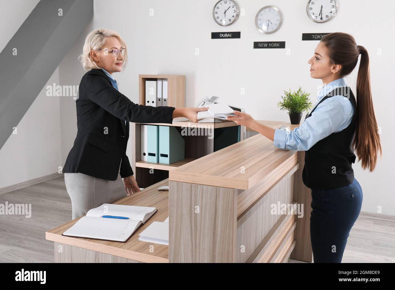 Female receptionist teaching trainee in hotel Stock Photo - Alamy